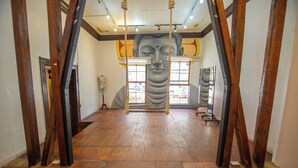 Quarto espaçoso com piso de madeira, uma janela grande e um mural de um rosto na parede.