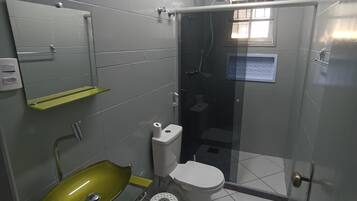 Um banheiro moderno com chuveiro em gabinete de vidro, pia verde e vaso sanitário branco.