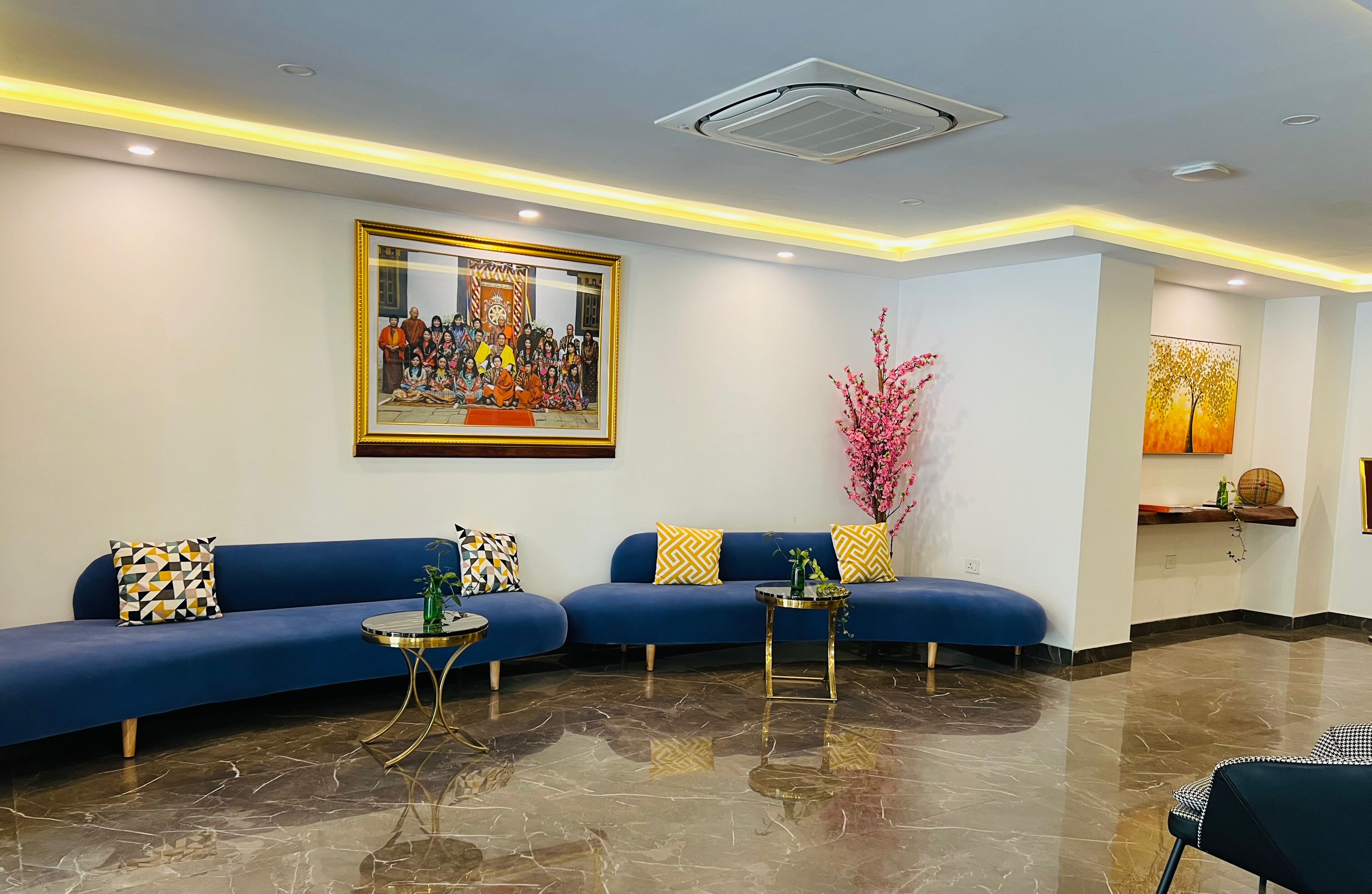 Um hall moderno com um sofá azul, uma mesa redonda e uma grande pintura emoldurada na parede.