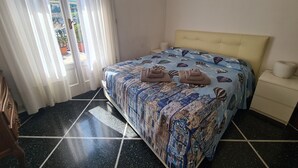 Quarto de hotel com cama, mesa de cabeceira, janela com cortinas e vista para o exterior.