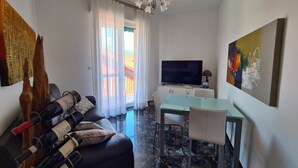 Uma sala de estar moderna com sofá, televisão, mesa de jantar e obras de arte.
