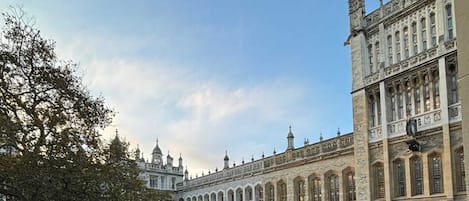 Um edifício grande e histórico, com fachada simétrica, várias janelas e uma bandeira no topo.