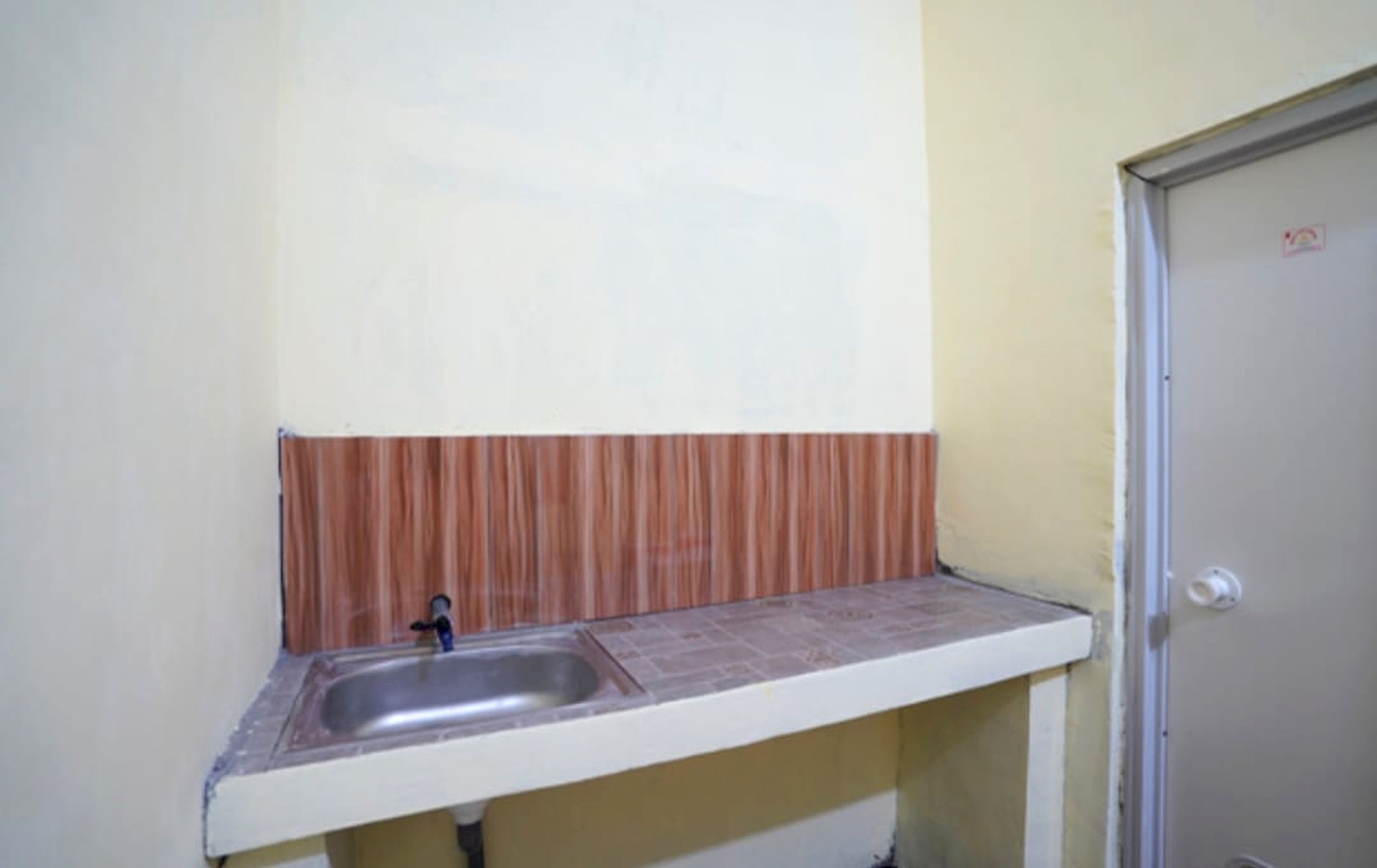 Um banheiro pequeno com uma pia, um espelho e uma porta.