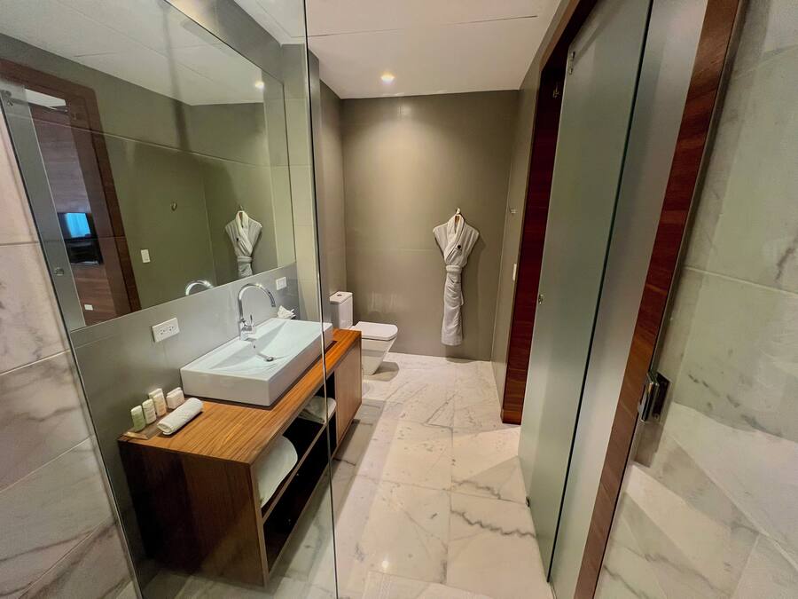 Uma casa de banho moderna com um espelho grande, uma pia e uma sanita.