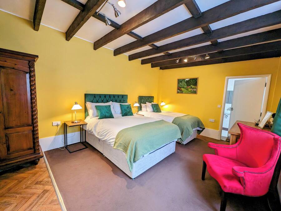 Quarto com cama, mesas de cabeceira, uma cadeira e um guarda-roupa de madeira.