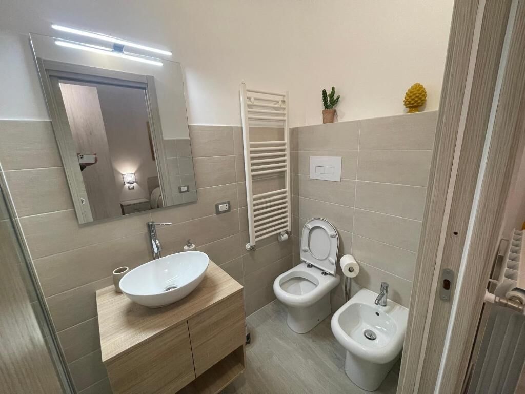 Casa de banho moderna com lavatório, sanita, bidé e porta-toalhas.