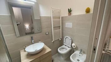Casa de banho moderna com lavatório, sanita, bidé e porta-toalhas.