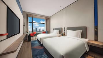 Quarto de hotel com duas camas, televisão, vista para a cidade e uma cadeira vermelha.