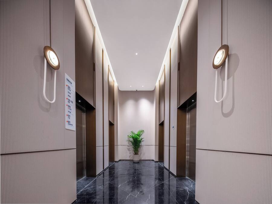 Um corredor moderno com piso de mármore, um vaso de planta e placas de sinalização nas paredes.