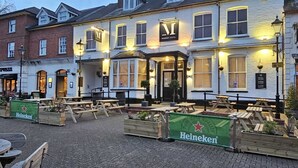 Um edifício com placa indicando o Hotel Market, com mesas ao ar livre e marca Heineken.