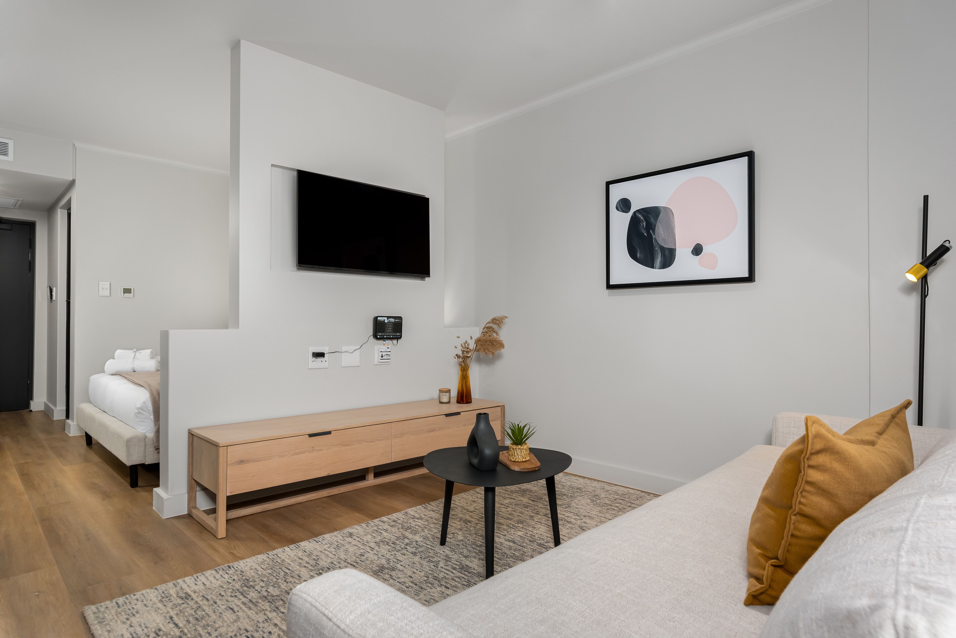 Uma sala de estar moderna com sofá, mesa de centro, televisão fixada na parede e um console minimalista.