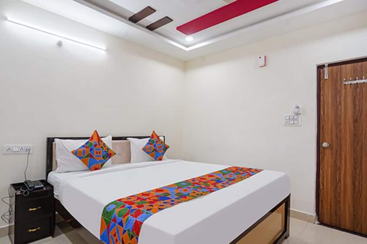 Um quarto com uma cama, uma mesa de cabeceira, uma porta de madeira e um teto com iluminação embutida.
