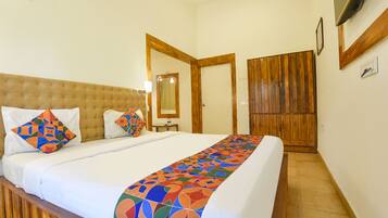 Quarto de hotel com cama grande, cabeceira de madeira, guarda-roupa de madeira e espelho na parede.