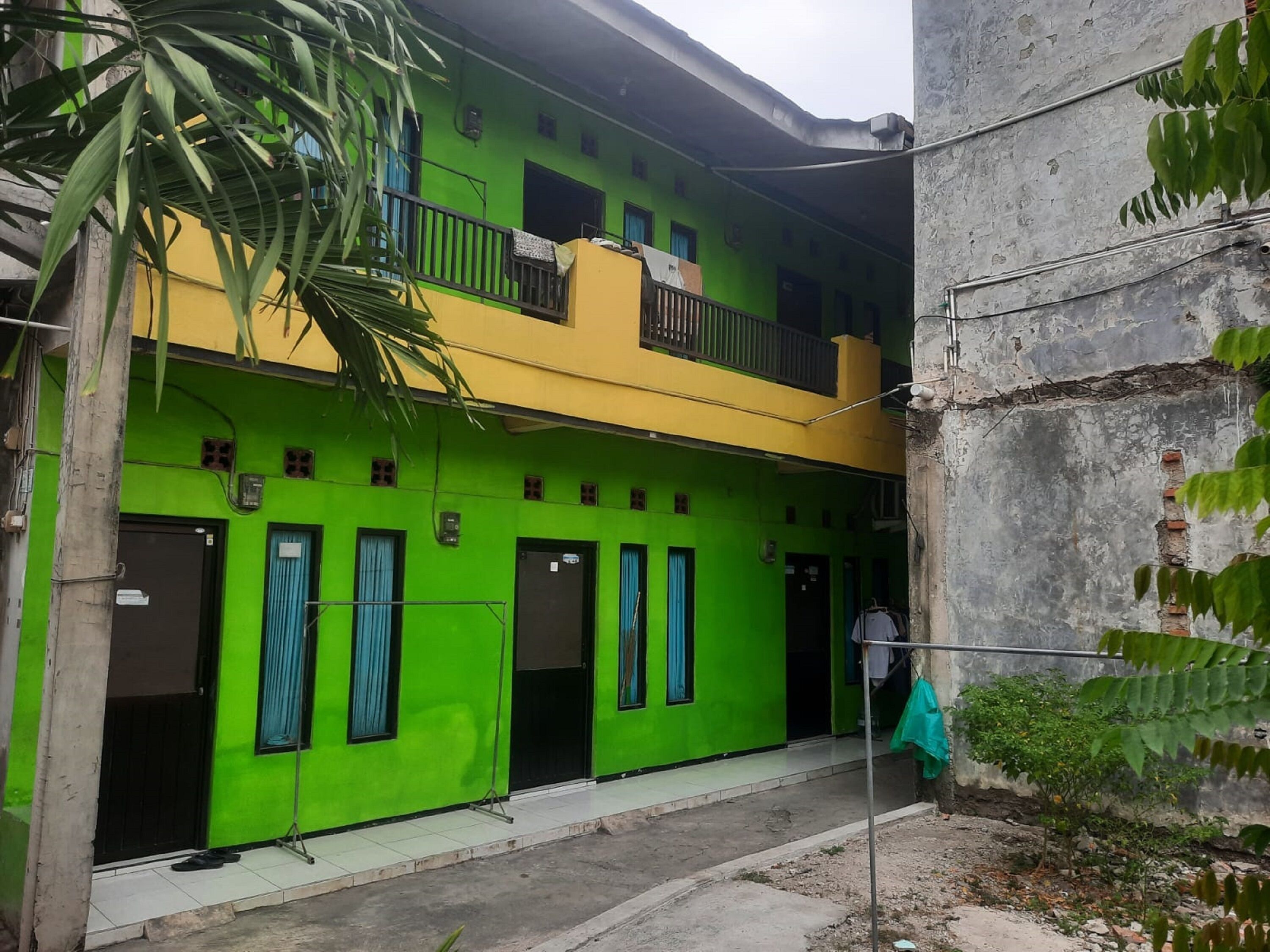 Edifício de dois andares com fachada verde e seção superior amarela.