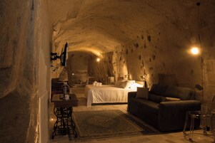 Um quarto acolhedor, em estilo de caverna, com uma cama, um sofá, uma escrivaninha e uma cadeira.
