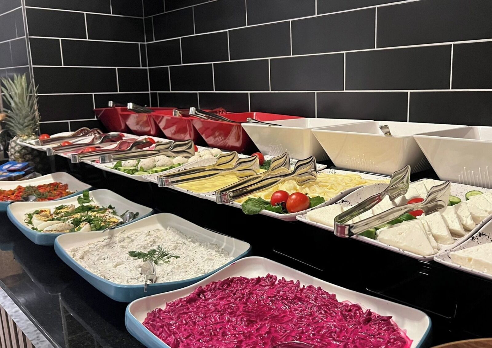 Buffet com diversos alimentos e utensílios de servir.