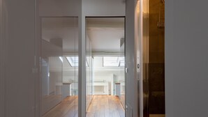 Um corredor com portas de vidro que dão para um quarto com claraboia.