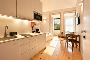 Cozinha compacta com micro-ondas, pia e pequena área de refeições com mesa e cadeiras.