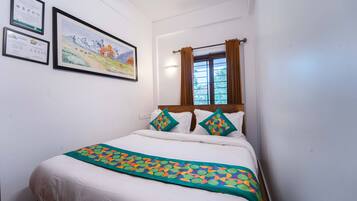 Uma cama bem arrumada com um cobertor colorido, um certificado emoldurado na parede e uma janela com cortinas.
