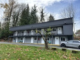 Um motel de dois andares com quartos numerados, varanda e estacionamento.