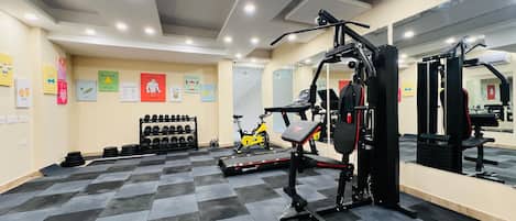 Academia com equipamentos de ginástica, halteres e bicicleta ergométrica.