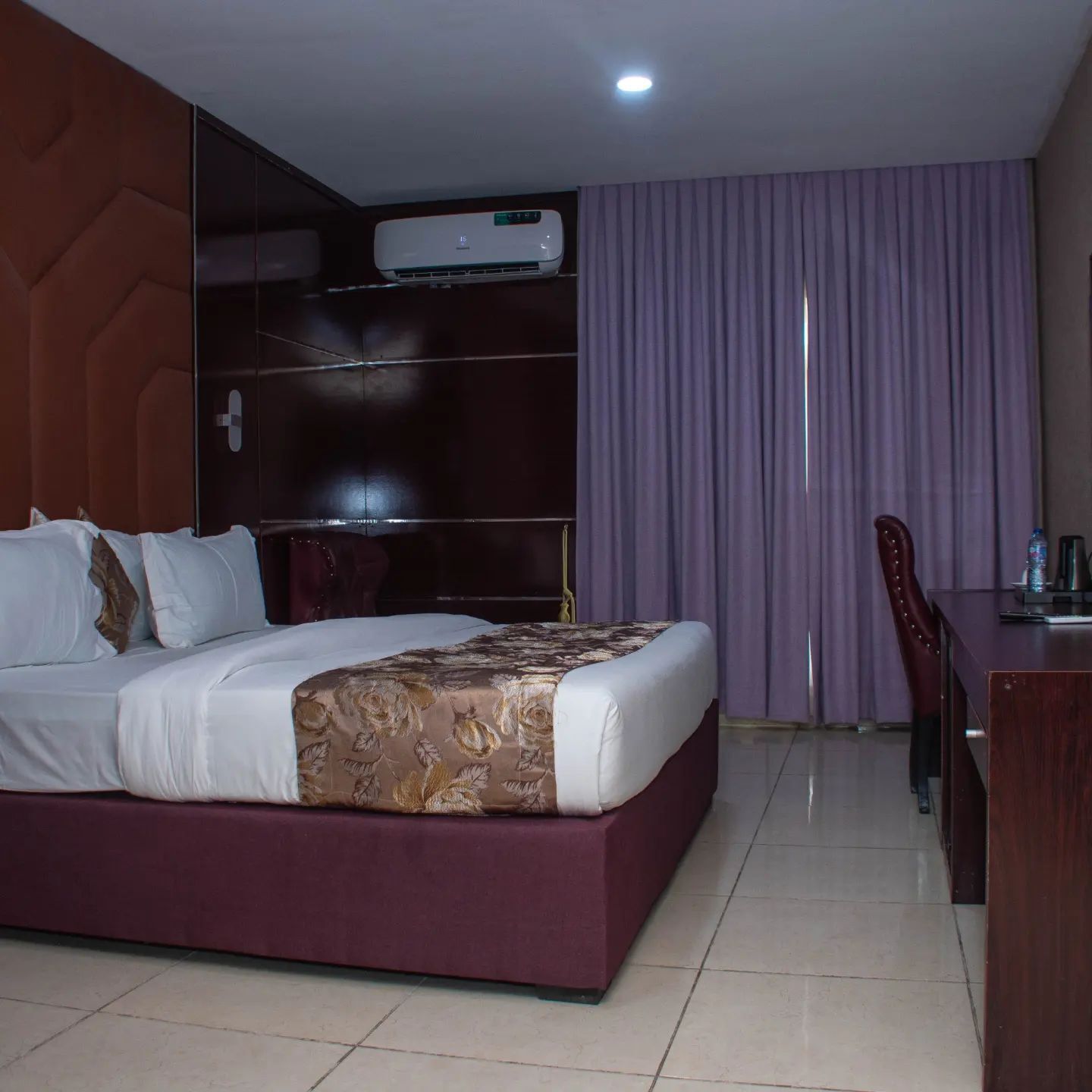 Quarto de hotel com uma cama grande, uma escrivaninha e um guarda-roupa.