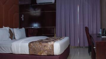Quarto de hotel com uma cama grande, uma escrivaninha e um guarda-roupa.