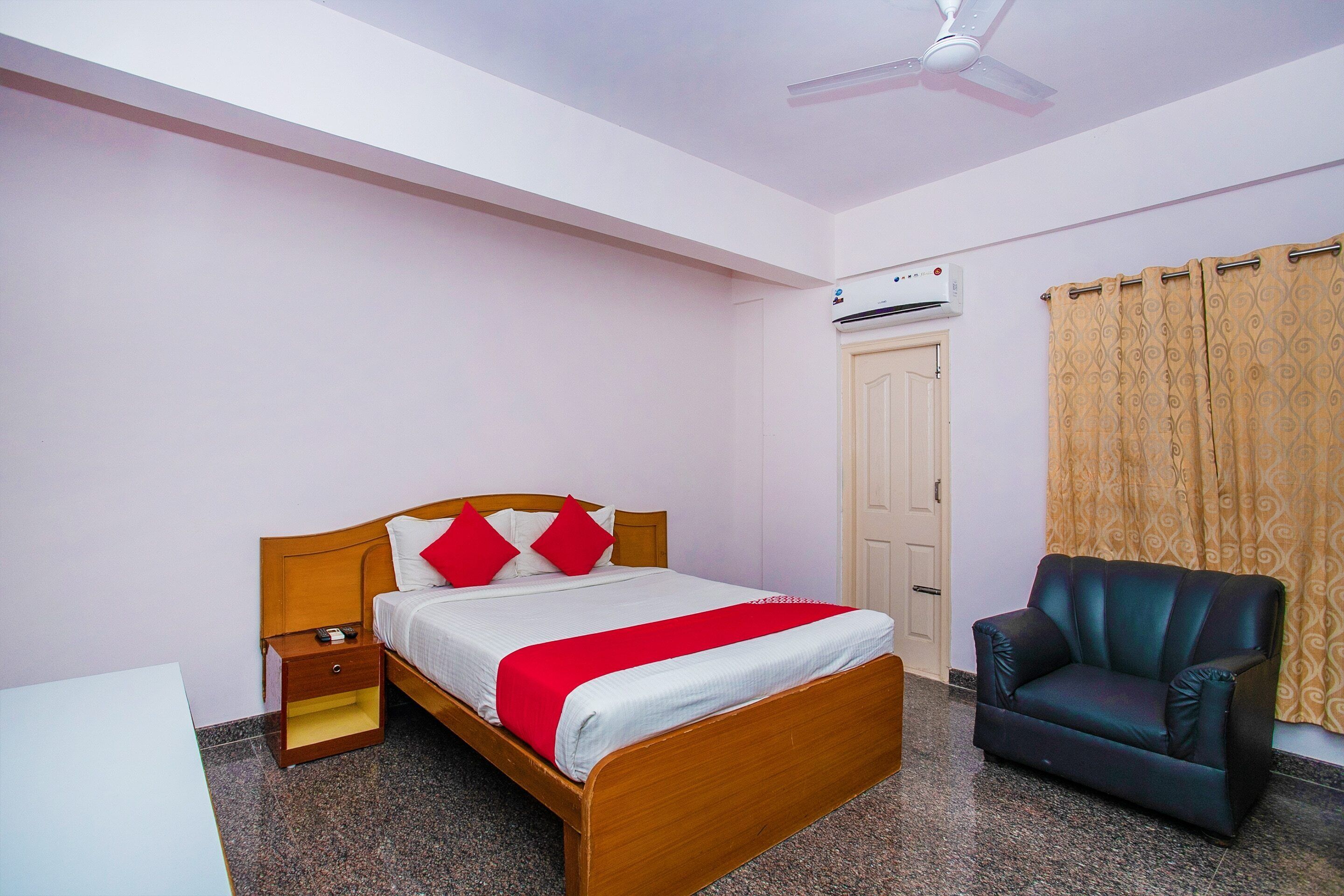 Quarto com cama de madeira, mesa de cabeceira, cadeira, ventoinha no teto e ar condicionado.