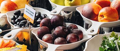 Buffet com diversas frutas e legumes, incluindo maçãs, laranjas e tomates.