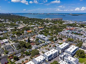 Vista aérea de uma área residencial com edifícios modernos, uma marina e um horizonte urbano ao longe.