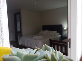 Quarto com cama, mesa de cabeceira e janela.