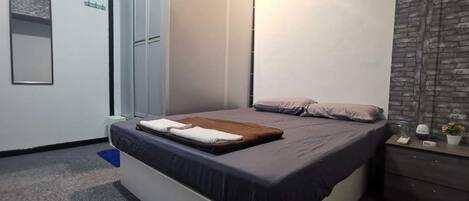 Um quarto com cama, guarda-roupa, escrivaninha e uma pequena planta.