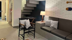 Uma sala de estar moderna com escada, sofá, poltrona e luminária.