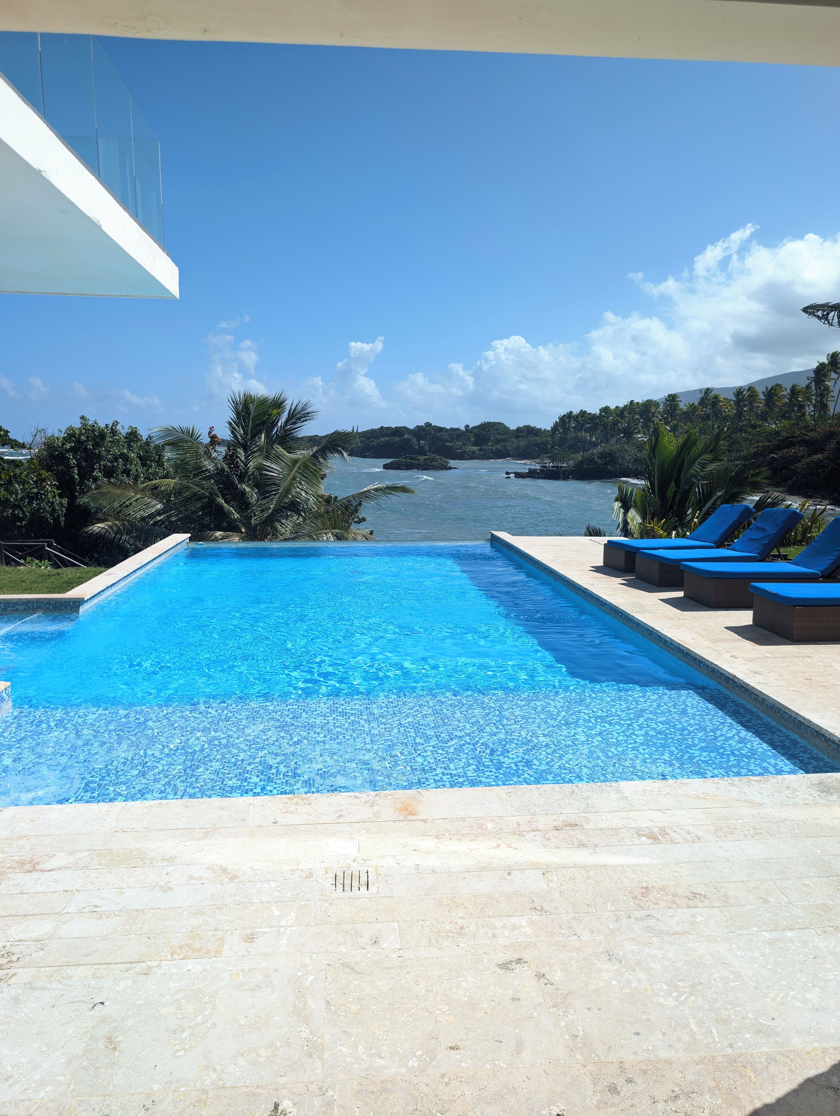 Piscina com vista para o mar e palmeiras.