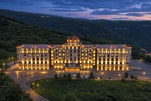 Um hotel grande com uma cúpula central, diversas alas e uma fachada bem iluminada.