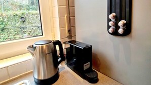 Cozinha com chaleira, torradeira e janela com vista para vegetação.