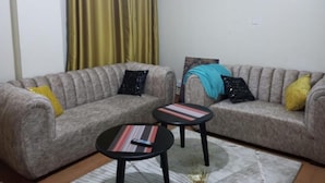 Sala de estar com dois sofás, uma mesa de centro e um candeeiro fixado na parede.