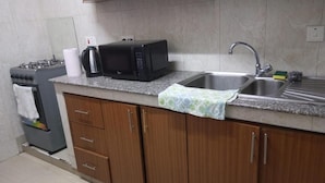 Uma cozinha com fogão a gás, micro-ondas, pia e armários de madeira.