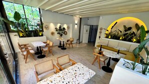 Interior moderno com área de jantar, cadeiras e mesas de madeira com acabamento em terrazzo.