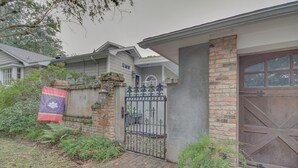 Uma casa residencial com fachada de tijolos, um portão de metal e uma porta de garagem de madeira.