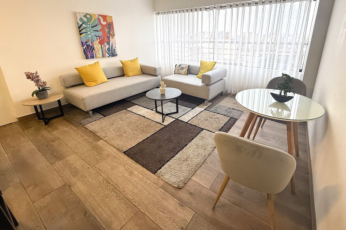 Uma sala de estar moderna com sofá, duas poltronas, uma mesa de centro e uma mesa de jantar.