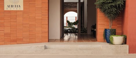 Entrada de hotel com fachada de madeira, varanda e placa com a inscrição "Aurelia Hotel".