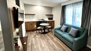 Um espaço compacto com cozinha compacta, uma mesa de jantar redonda e um sofá com almofadas.