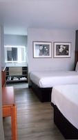 Quarto de hotel com cama, escrivaninha, espelho e duas quadros na parede.