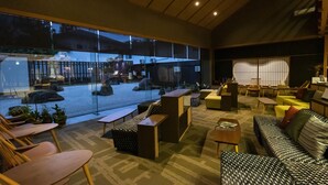 Um espaço interior moderno com área de estar, balcão de recepção e grandes janelas com vista para o exterior.