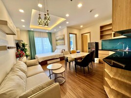 Quarto de hotel moderno com cama, sofá, mesa de jantar, cadeiras e cozinha.