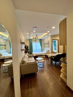 Quarto de hotel moderno com sofá, mesa de jantar, mesa redonda pequena e cama.