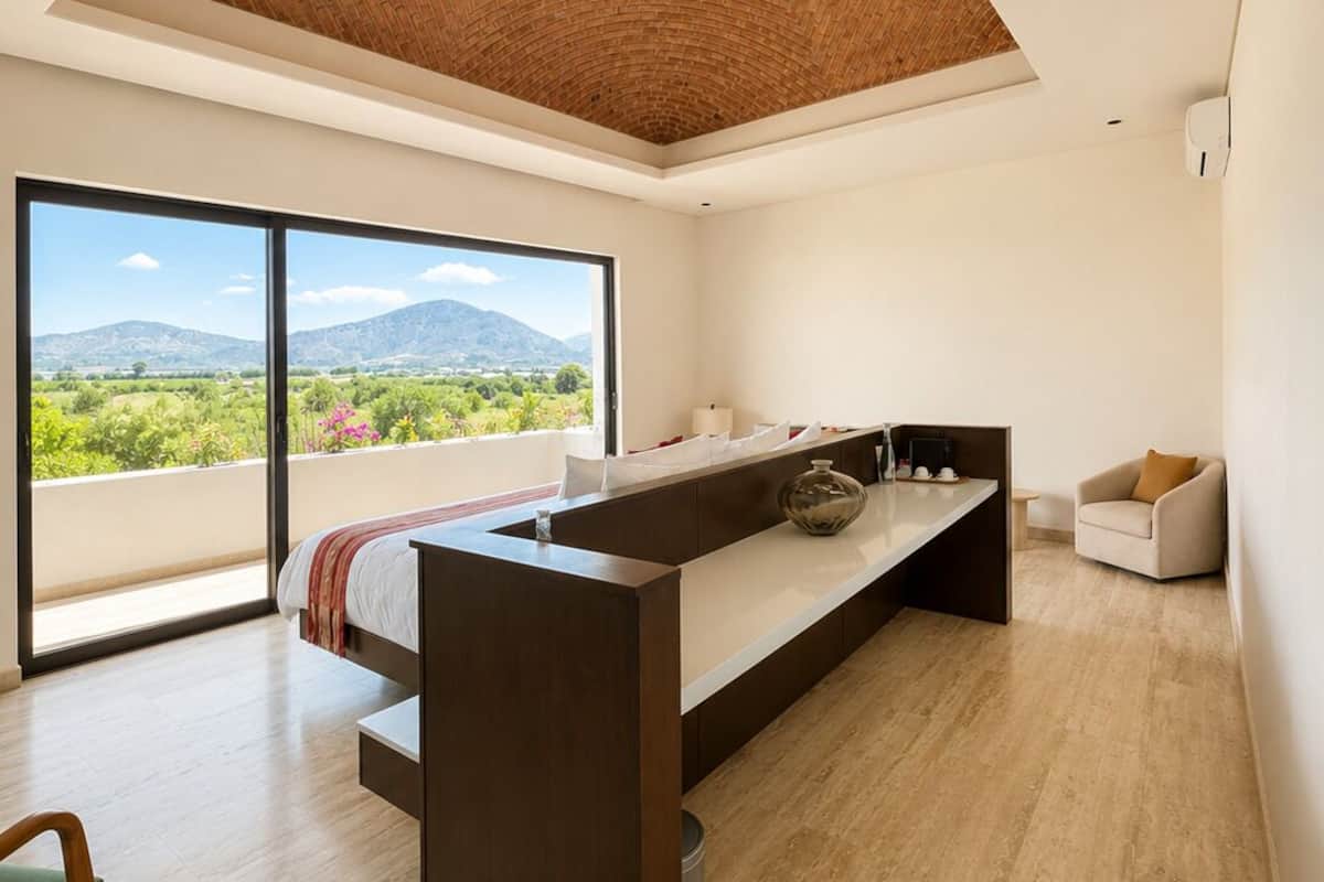 Quarto moderno com uma janela grande, teto de madeira e um banco embutido.