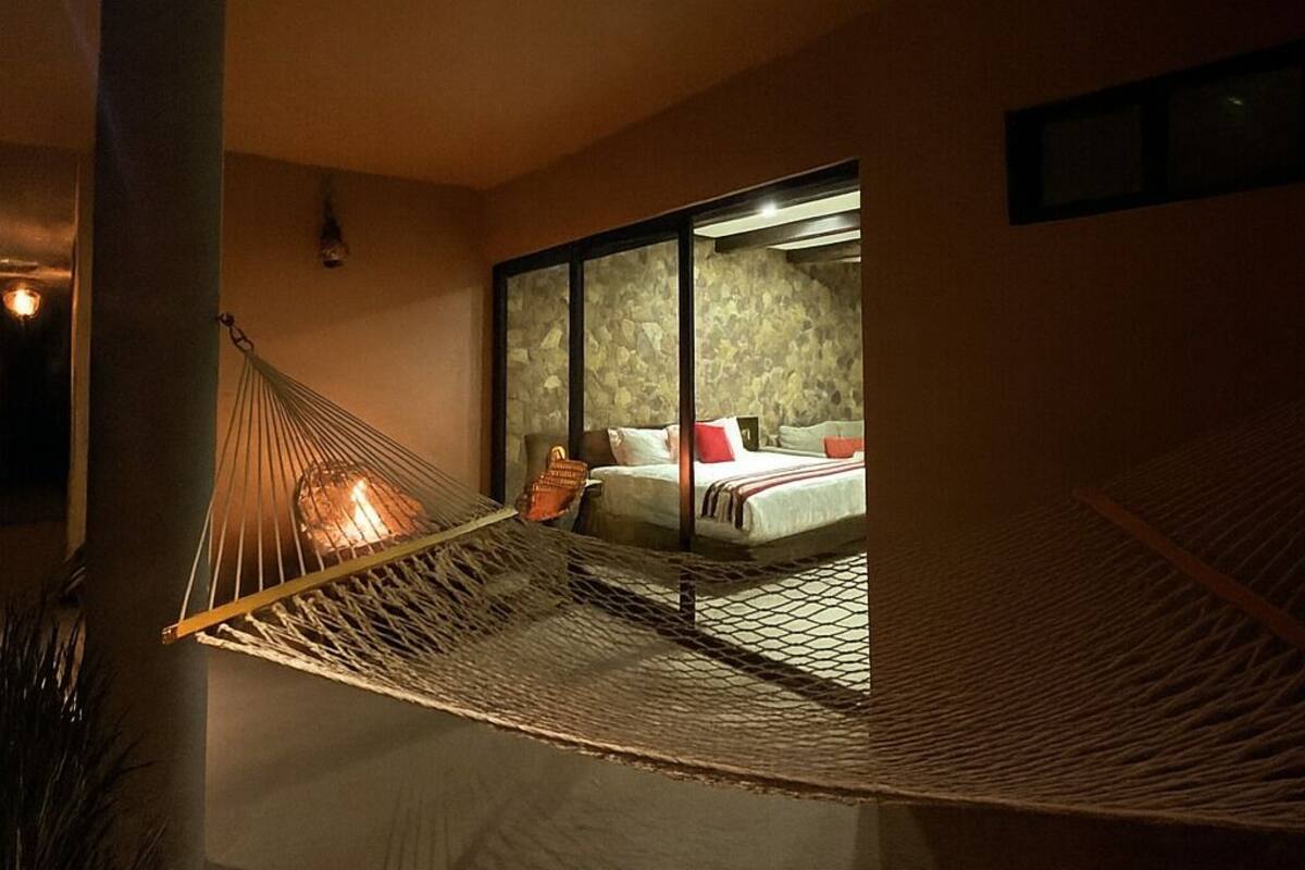 Uma rede em um quarto com uma cama e uma parede de pedra.