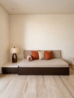Quarto moderno com uma cama, uma mesa de cabeceira com abajur e uma pequena mesa redonda.